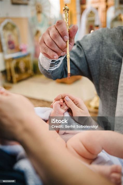 아기의 세례식 작은 아기 손의 근접 촬영 세례성사 대모는 아이를 품에 안고 있다 사제는 손을 아이의 손과 다리로 뻗는다 사원 정교회 3 명에 대한 스톡 사진 및 기타 이미지