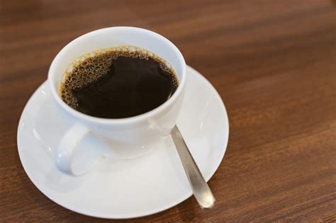 빈티지 부드러운 음색 사람들을 위해 깨어 검은 카페인에에서 아침에 커피가 게에서 창 근처 나무 테이블에 화이트 커피 컵에 거품과 뜨거운 에스프레소를 닫습니다 갈색에 대한