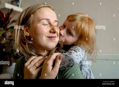 Daughter Embracing Mother From Behind And Kissing Her On Cheek At Home