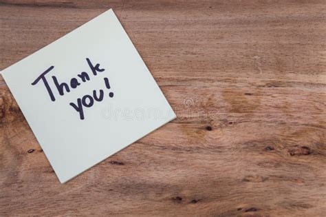 a thank you note is written on a piece of paper and placed on a wooden