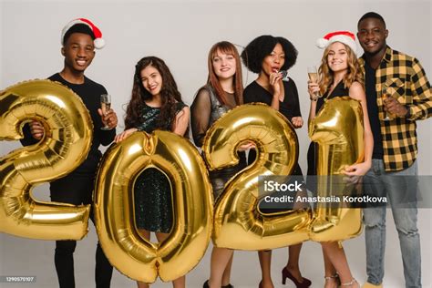 새로운 2021 년은 금색 숫자를 들고 샴페인을 마시는 산타 모자에 쾌활한 젊은 이들의 그룹이 오고있다 20 24세에 대한 스톡 사진 및 기타 이미지 Istock