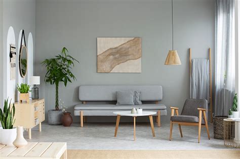 현대 포스터 방석과 라운지 안락의 자 나무 커피 테이블 및 밀 짚 램프 회색 거실 인테리어의 실제 사진 밀짚에 대한 스톡 사진 및 기타 이미지 Istock