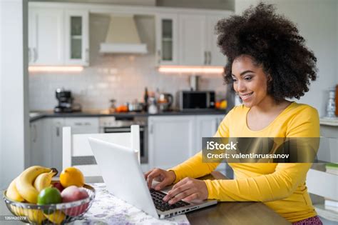 아름다운 아프리카 계 미국인 젊은 여자 앉아 에 집 과 미소 와 입력 에 그녀의 노트북 20 24세에 대한 스톡 사진 및 기타