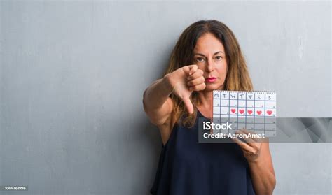 중간 나이 히스패닉 여자 회색 그런 지 벽 성 난 얼굴로 기간 일정을 잡고 서 음수 기호 거절 거절 개념으로 혐오를 보여주는 개념에 대한 스톡 사진 및 기타 이미지 Istock