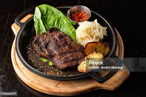 구운 황금 감자를 곁들인 구운 스테이크는 어두운 배경에 신 양배추와 붉은 소스를 곁들인 채 제공됩니다 맛있는 레시피 돼지 고기 필레 요리 0명에 대한 스톡 사진 및 기타