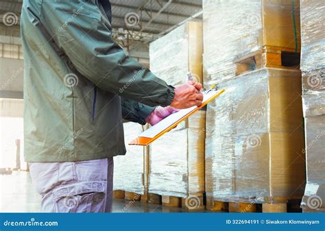 Warehouse Worker Holds A Clipboard And Checks A Package Boxes Pallets