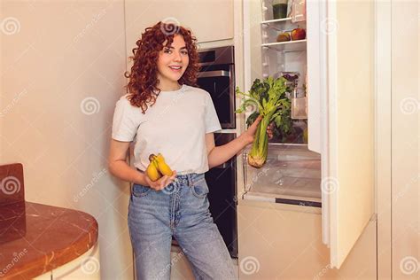 Ginger Girl Unpacking And Putting Food To The Fridge Stock Image
