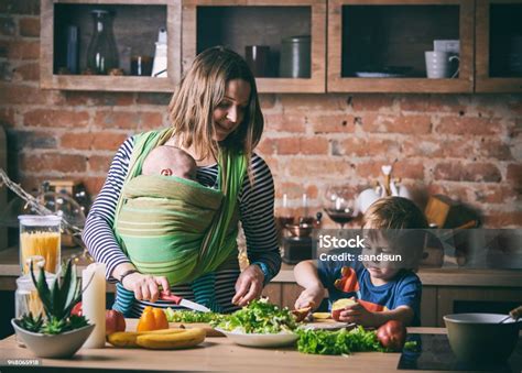 행복 한 젊은 가족 두 아이 사랑 스러운 유아 소년과 아기 슬링 함께 햇볕이 잘 드는 부엌에서 요리와 아름 다운 어머니 가족에 대한 스톡 사진 및 기타 이미지 Istock