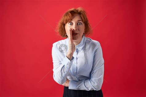 美丽的红发女人在红色背景向摄像头低语高清图片下载 正版图片503676193 摄图网