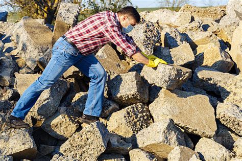 一个人用一堆石头和碎混凝土，搬运建筑碎片