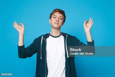 요가 제스처에 손을 잡고 캐주얼 옷에 젊은 남자의 초상화 스튜디오에서 파란색 벽 배경에 고립 명상 휴식 사람들은 진심으로 감정 라이프 스타일 개념입니다 복사 공간을 모의