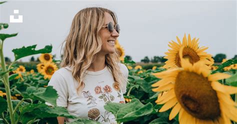흰색과 여러 가지 빛깔의 꽃 셔츠를 입은 여자가 노란 해바라기 밭에 서서 웃고 있습니다 사진 Unsplash의 무료 해바라기 이미지