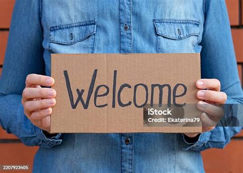 벽돌 벽 배경에 환영이라는 단어가 적힌 골판지 조각을 들고 있는 여자 검은색에 대한 스톡 사진 및 기타 이미지 검은색 낱말 데님 Istock
