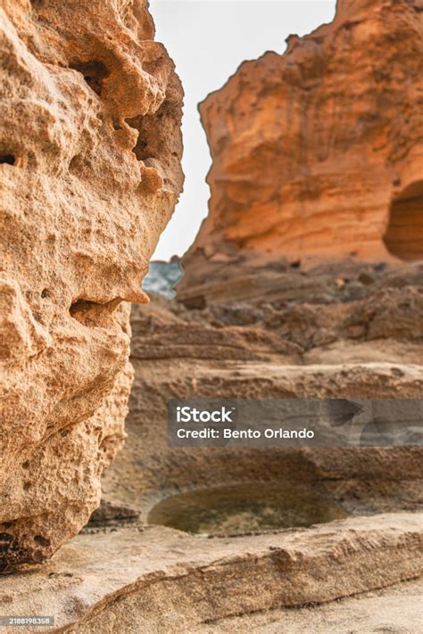 미묘한 맑은 하늘 아래 독특한 침식 패턴과 따뜻한 흙 색조를 보여주는 험준한 사막 풍경의 놀라운 자연 암석층은 자연의 지질학적 경이로움의 아름다움을 포착합니다 0명에 대한