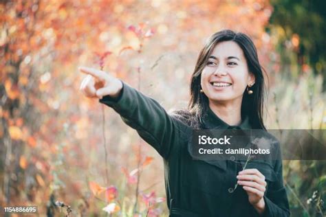 Bokeh에 화려한 나뭇잎으로가을 배경에 긴 자연 검은 머리를 가진 꿈꾸는 아름 다운 소녀 영감을 소녀 포인트 손가락 떨어져 가을 숲에서 생생한 단풍 중 여성의 아름다움