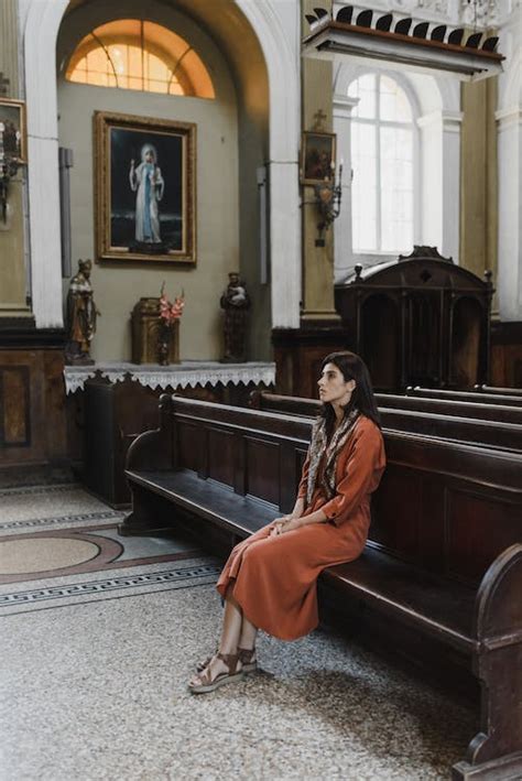 A Woman Sitting On Wooden Bench While Praying In The Church · Free