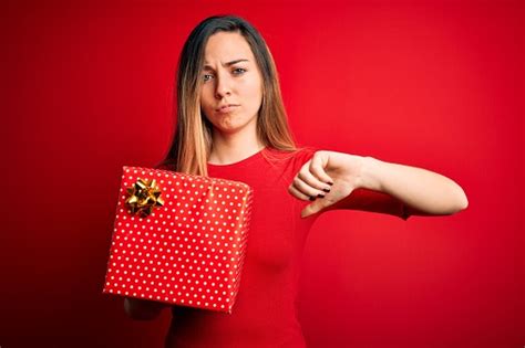 화가 얼굴 엄지 손가락으로 싫어하는 것을 보여주는 부정적인 기호 거부 개념과 빨간 배경 위에 생일 선물을 들고 푸른 눈을 가진