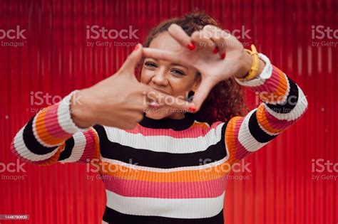 행복한 흑인 여성과 손가락 프레임은 빨간색 배경에 재미있는 얼굴 표현을 위해 눈 위에 있습니다 패션 만화 및 긍정적 인 관점으로 남아프리카 공화국에서 온 여성과 장난스러운