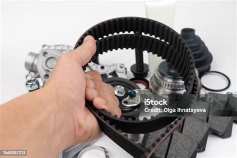 자동차 엔진의 가스 분배 시스템의 타이밍 벨트 및 텐션 롤러 자동차 유지 보수의 개념 마스터의 손은 흰색 배경에 예비 부품의 배경에 타이밍 벨트를 잡고 있습니다 강철에 대한