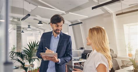 잘 생긴 청년이 공책에 글을 쓰고 직장에서 여자 동료와 이야기하면서 웃고 있다 사진 Unsplash의 동료 이미지