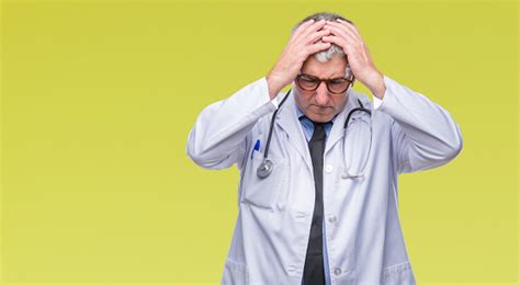 잘생긴 노인 의사 남자와 고립 된 배경 두통 필사적으로 고통을 고통 및 편두통 때문에 스트레스 머리에 손을 걱정하는에 대한 스톡