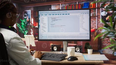 woman in home office looking at ui on pc screen typing and executing programming code coding