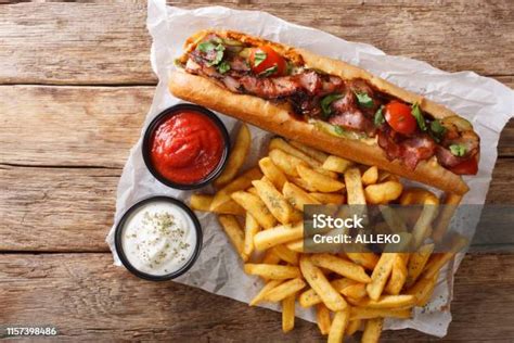 베이컨과 야채를 곁들인 소박한 스타일의 핫도그에서 감자 튀김과 소스를 클로즈업하여 드실 수 있습니다 가로 맨 위 보기 꼭대기에