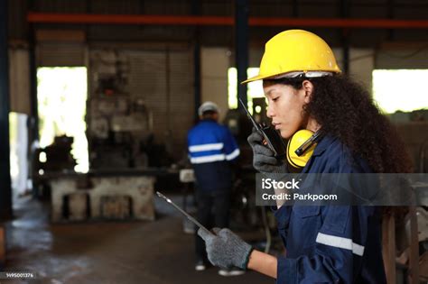 중공업 제조 공장에서 선반 금속 기계를 제어하거나 유지 보수 작업을 하는 동안 태블릿이 있는 워키토키 라디오를 사용하는 보호복을