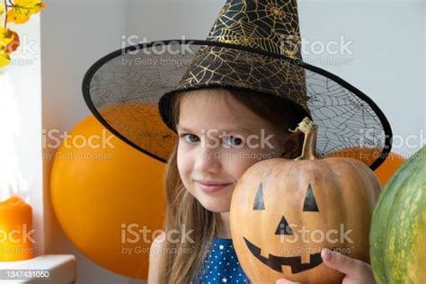 잭 오 랜턴 얼굴과 호박을 들고 마녀 의상을 입은 어린 소녀의 초상화 집에서 할로윈을 준비하는 검은 모자를 쓴 아이 가족 휴가 파티 10월에 대한 스톡 사진 및 기타 이미지