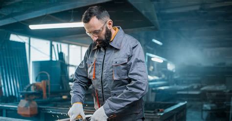 작업복을 입은 금속 산업 노동자는 공장에서 철강 제품을 연마하고 금속 가공을하고 있습니다 금속 제품 제조에 잘 생긴 장인 고품질 사진 사진 Unsplash의 지시 이미지