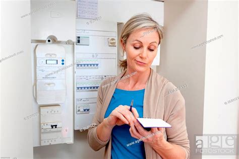 Woman Reading The Counter Of An Electricity Meter To Determine The Domestic Electricity Used