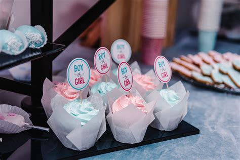 파란색과 분홍색 크림을 곁들인 컵 케이크 성별 파티를위한 과자가있는 테이블 베이비 샤워 파티 장식 맛있는 리셉션 축하 개념입니다 트렌디 한 캔디 바 사탕 디저트 테이블 소녀