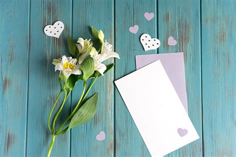 빈 종이와 흰색 색상의 자연 꽃 파란색 나무 배경에 봉투를 모의 빈 텍스트 프레임입니다 꽃과 인사말 카드 디자인입니다 나무