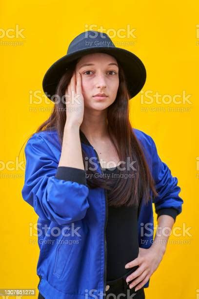 노란 배경에 검은 모자와 파란색 재킷을 입은 젊은 백인 소녀의 수직 사진 초상화 얼굴 위에 손 20 24세에 대한 스톡 사진 및 기타 이미지 Istock
