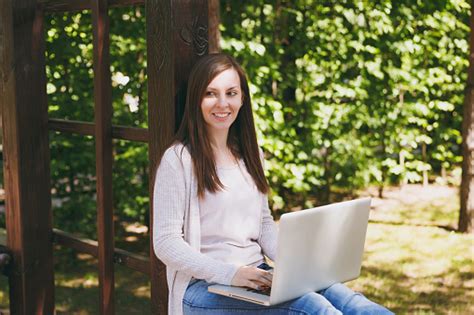 가벼운 캐주얼 옷에 젊은 성공적인 사업가 봄 자연에 야외 거리에 도시 공원에서 현대 노트북 Pc 컴퓨터에서 작업 하는 여자를 웃 고 모바일 사무실입니다 프리랜서 비즈니스