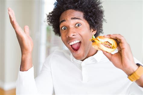 아프리카계 미국인 배고픈 남자 점심 식사를 위해 햄버거 매우 행복 하 고 흥분 승자 표현 축 하 하는 승리 비명 큰 미소와 손을