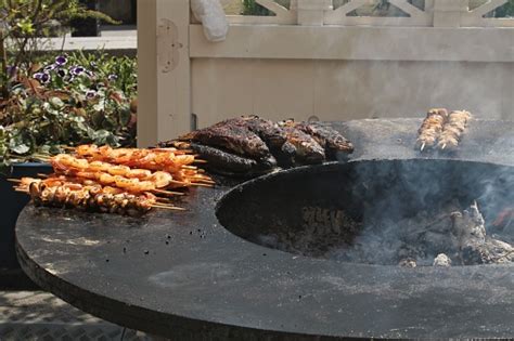 해산물 조각은 원뿔 모양의 그릇 모양으로 화덕 표면에서 조리됩니다 새우와 새우를 곁들인 그릇 모양의 납작한 그릴 야외 바베큐