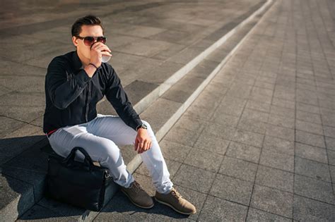 안경에 조용 하 고 평화로운 젊은 사람이 단계에 앉아 하 고 앞으로 그는 컵에서 마신다 그것은 밖에 서 밝은입니다 거리에 대한 스톡 사진 및 기타 이미지 Istock