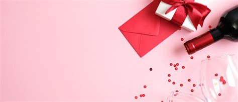 발렌타인 데이 로맨틱 한 저녁 식사 개념입니다 와인 샴페인 한 병 두 잔 선물 상자 사랑의 편지와 분홍색 배경에 색종이 봉투와 함께 상단보기 테이블 설정 플랫 레이 상단
