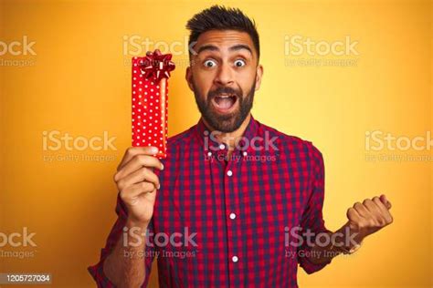 아랍 인도 히스패닉 남자 들고 발렌타인 선물 위에 서 고립 된 노란색 배경 비명 자랑 과 축하 승리와 성공 매우 흥분 응원 감정