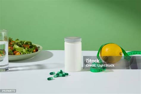 녹색 배경에 정면도의 창의적인 디자인 템플릿 위에 표시된 체중 감량 약 병이 있는 흰색 테이블 측정 테이프 옆 녹색 및 신선한 재료 0명에 대한 스톡 사진 및 기타 이미지