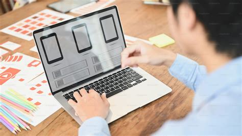 남자의 자른 이미지는 나무 테이블의 화면에 인터페이스 아이콘이 있는 컴퓨터 노트북을 사용하고 있습니다 사진 Unsplash의 휴식 이미지