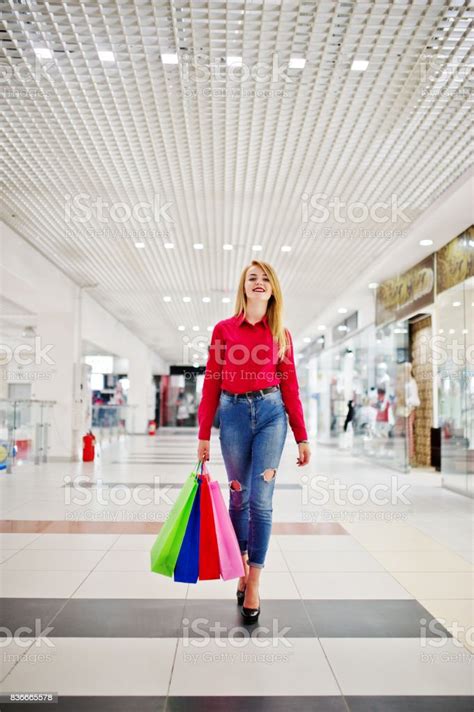 빨간 블라우스에 아름 다운 젊은 여자의 초상화는 캐주얼 청바지와 하이 힐 쇼핑몰에서 쇼핑백과 함께 포즈를 찢 어 가방에 대한 스톡 사진 및 기타 이미지 Istock