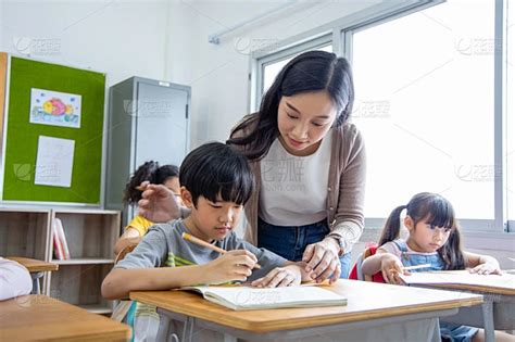 女生和男生在教室里做笔记。年轻的女教师给小学生提供学习多样性的建议。回归学校理念素材 花瓣网