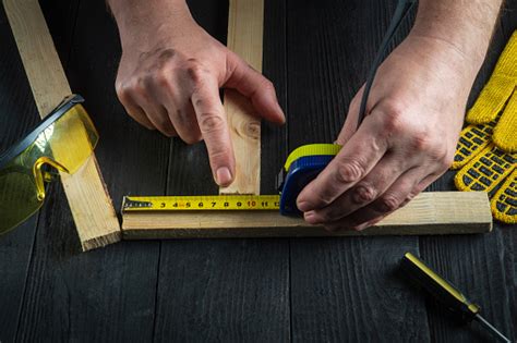 목수 또는 목공인은 건설 테이프를 사용하여 나무 조각의 길이를 측정합니다 직장에서 주인의 손 클로즈업 목공 작업장의 작업 환경 개선에 대한 스톡 사진 및 기타 이미지