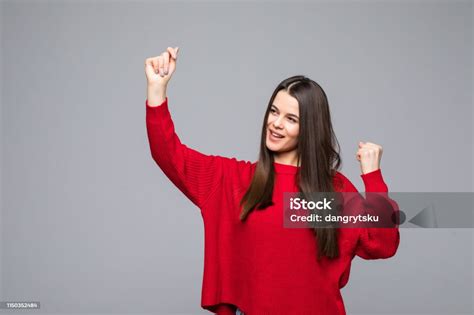 활기찬 여자의 초상화는 행복으로 주먹을 쥔 당신의 미소를가지고 캐주얼 빨간 스웨터를 입고 소녀 승리 복권 흰색 배경 위에 고립 승리의 개념입니다 겨울에 대한 스톡 사진 및