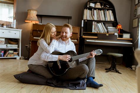 남자가 그의 젊은 아름 다운 여자를 위한 어쿠스틱 기타를 연주 가정의 방에 대한 스톡 사진 및 기타 이미지 가정의 방 거실 기타 현악기 Istock