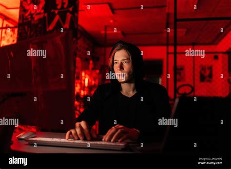 Front View Of Focused Hacker Man In Black Sweatshirt Using Laptop And