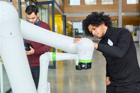 Engineers Working With A Robotic Gripper Arm In A Modern Industrial Setting Stock Image Image