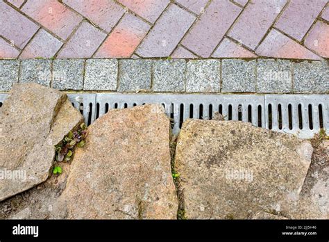 Iron Lattice Line Of Drainage System Of Pedestrian Sidewalk Made Of Stone Tiles Decorated With